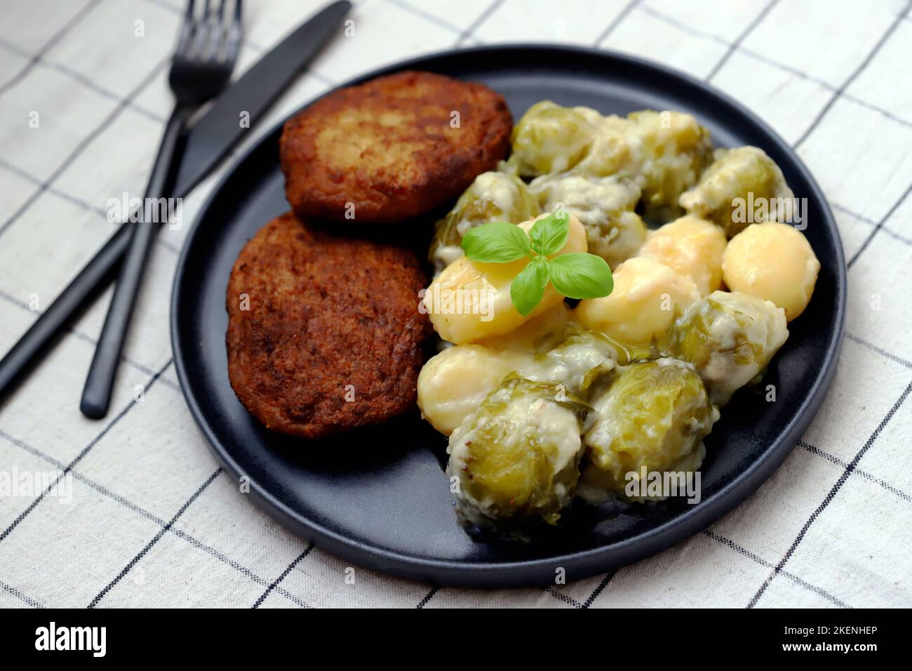Schnitzels with potatoes and Brussels sprouts in white sauce. A dish of ...