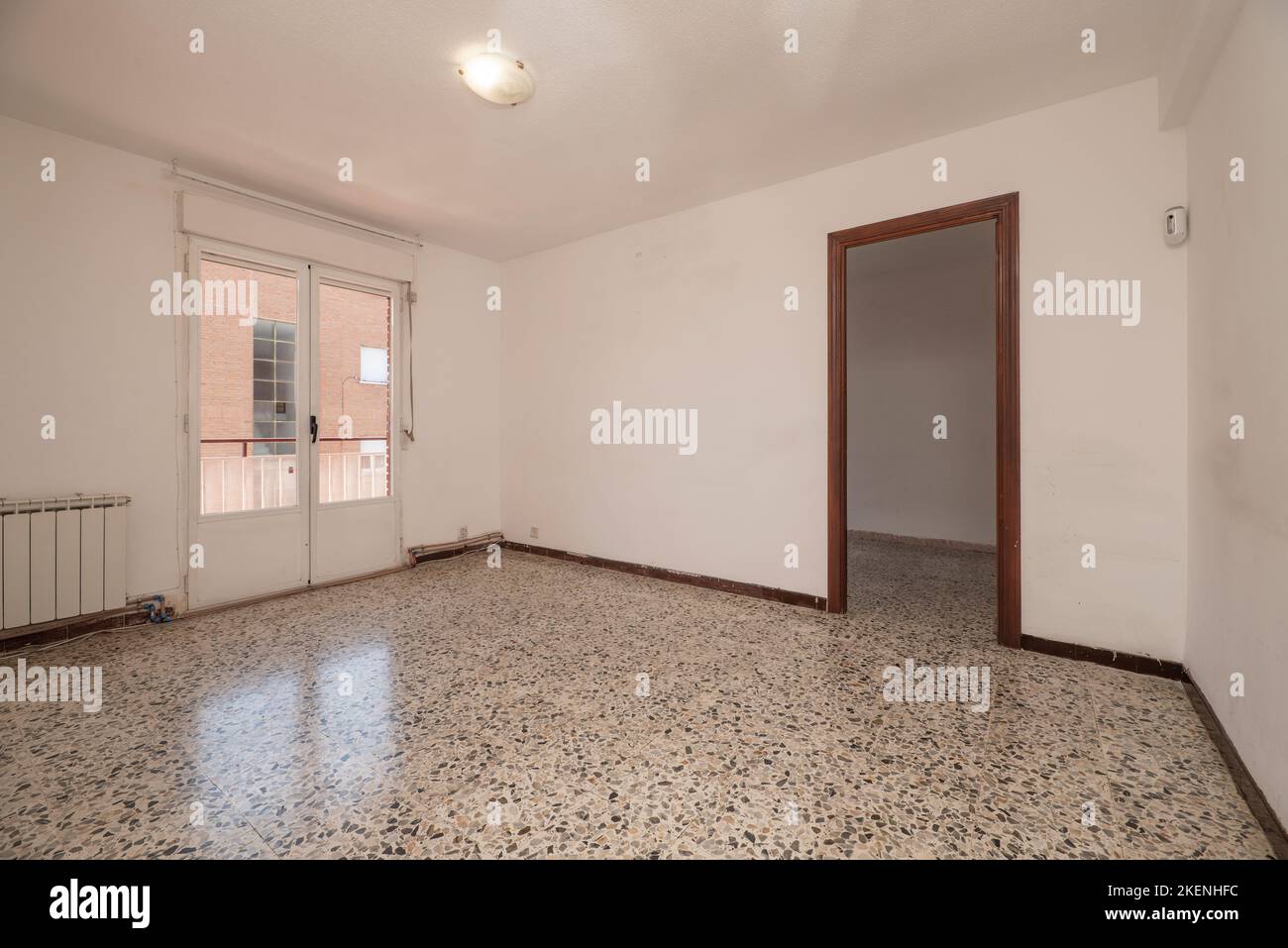 Empty room with gray terrazzo floors and white wooden doors leading to ...