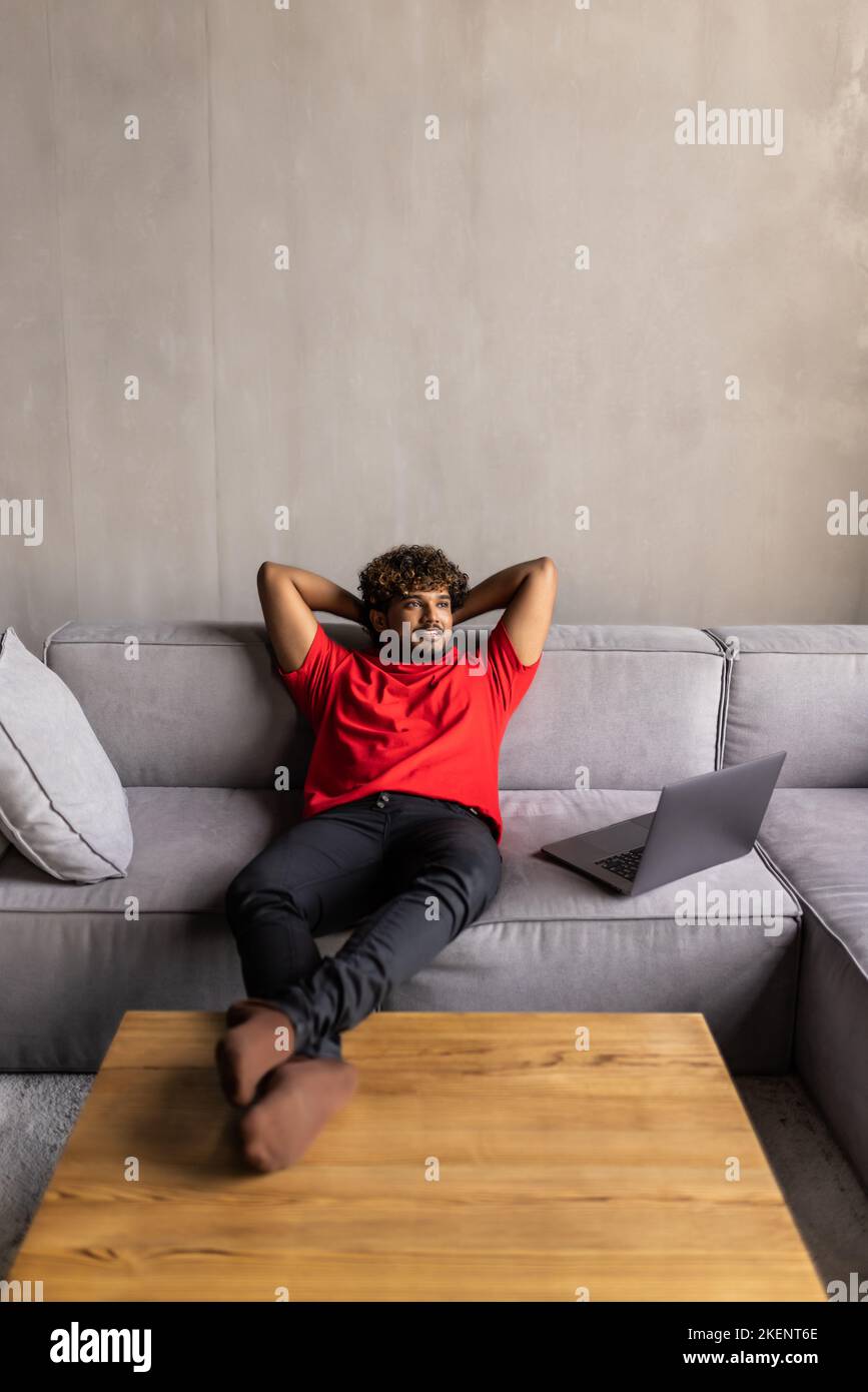 Satisfied relaxed young indian man chilling on sofa in living room ...