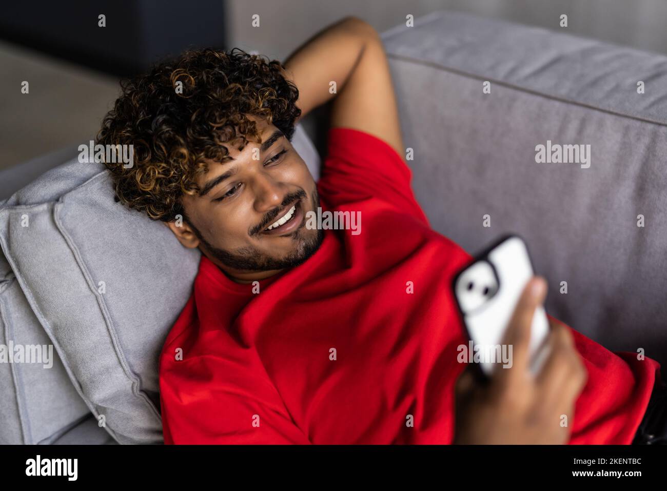 Young indian man have video call conversation on the phone lying at ...