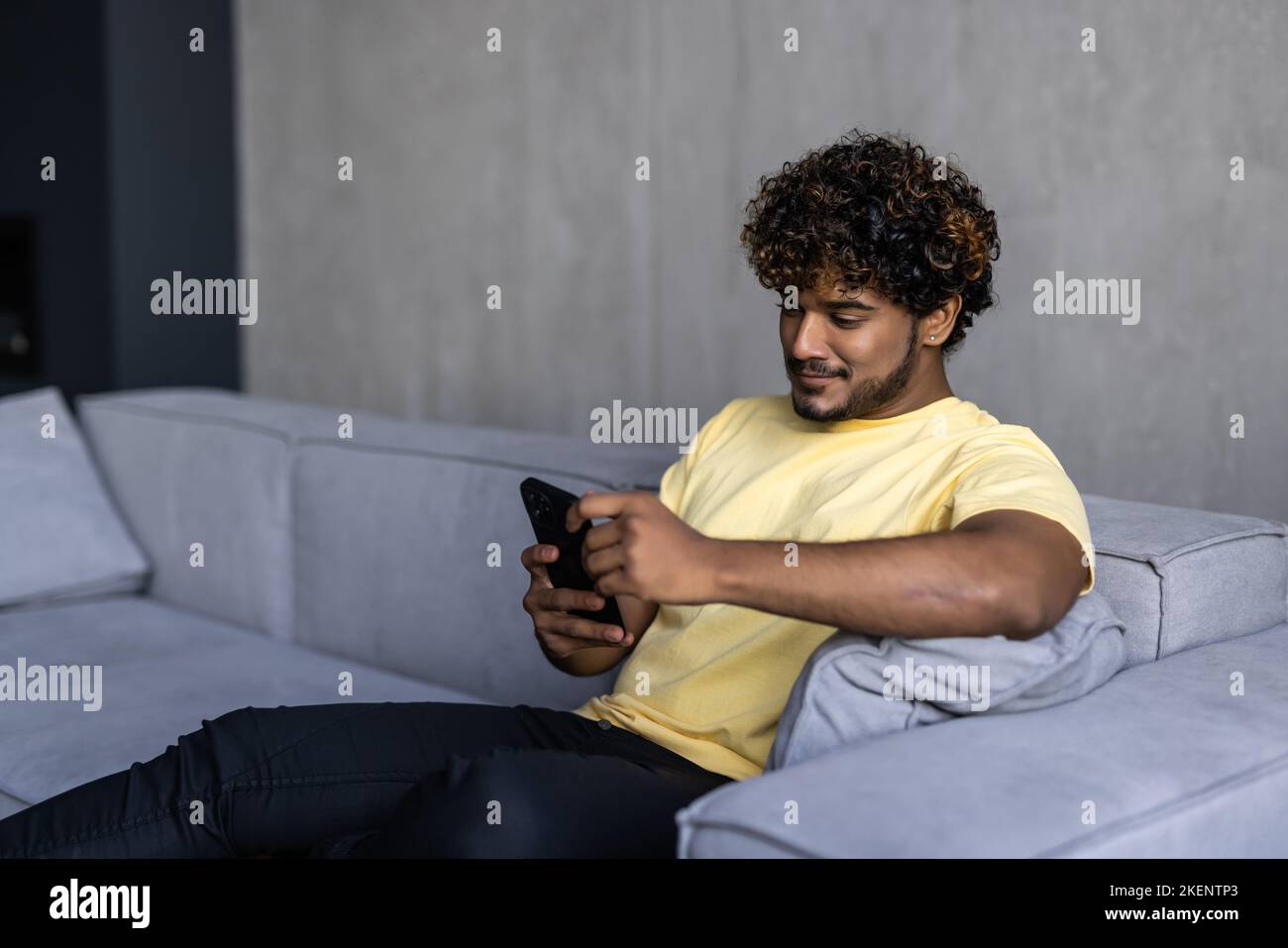 Young indian boring man with headphones on his neck holding phone and ...