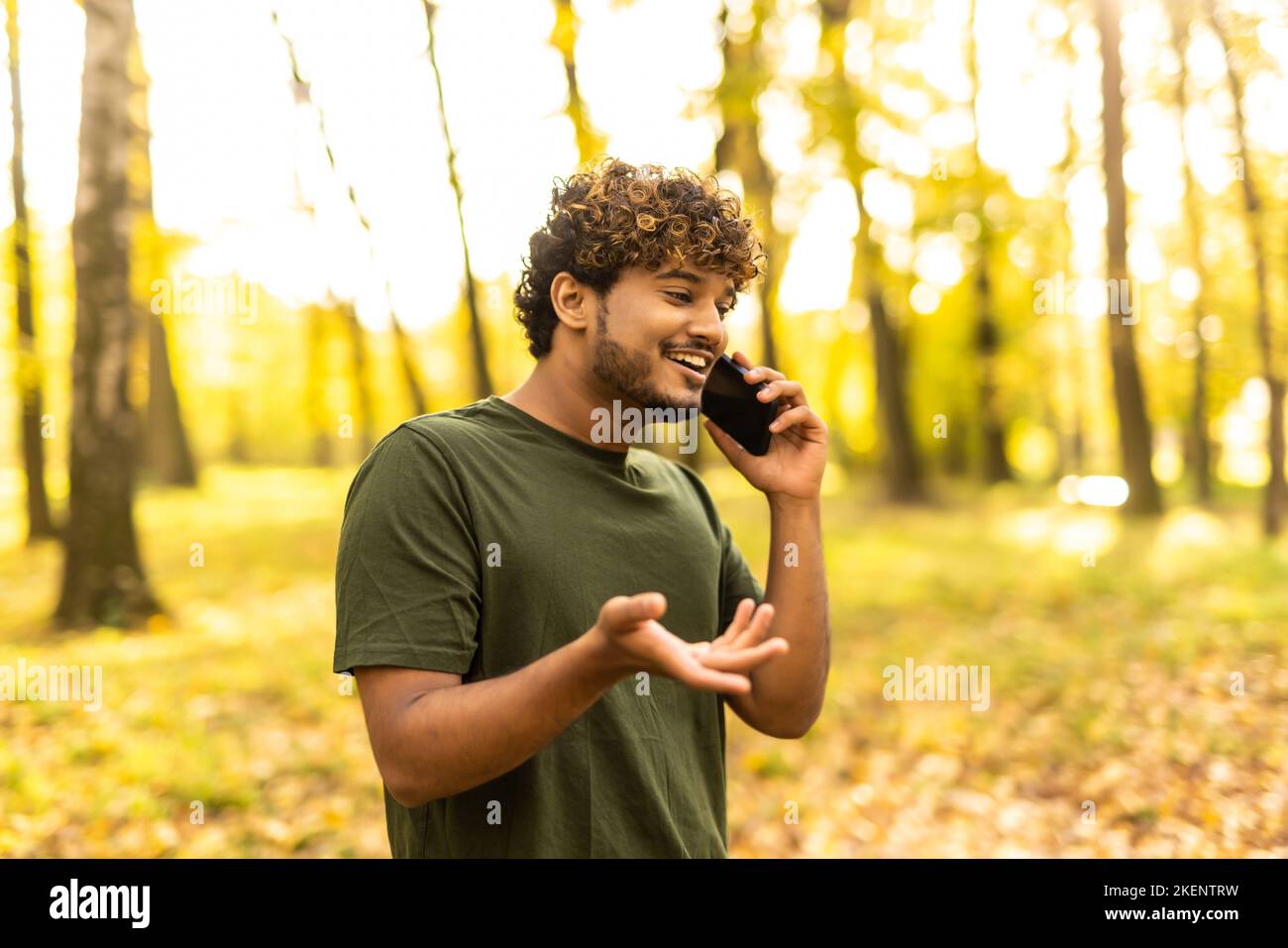 Young Indian man talking on smartphone and smiling on the street Stock ...