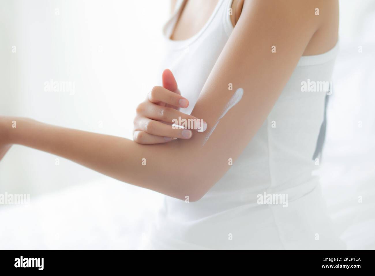 Beautiful young asian woman happy applying cream or lotion with ...