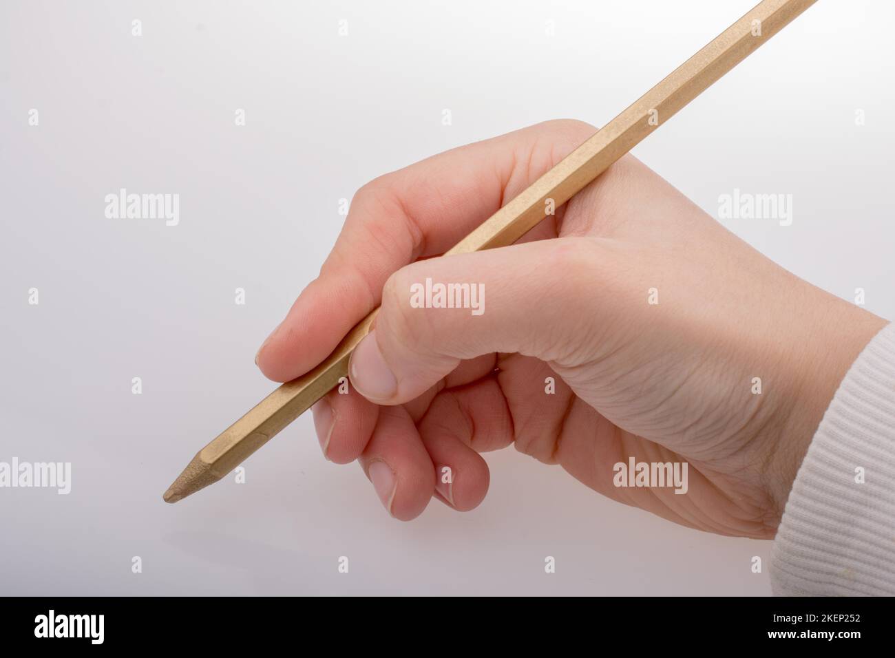 Hand holding a gold color pencil on a white background Stock Photo - Alamy