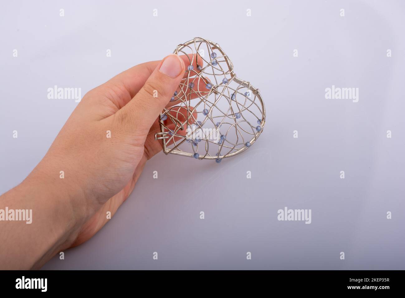 Heart shaped silver color metal wire cage in hand Stock Photo - Alamy