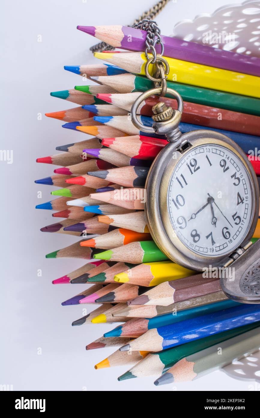 Retro style classic pocket watch and color pencils on white background ...