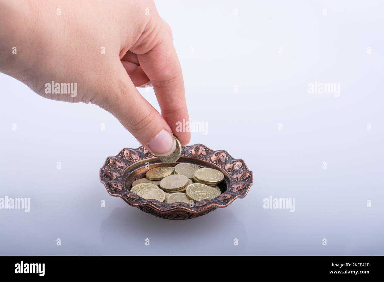Hand giving away money to a metal bowl Stock Photo - Alamy