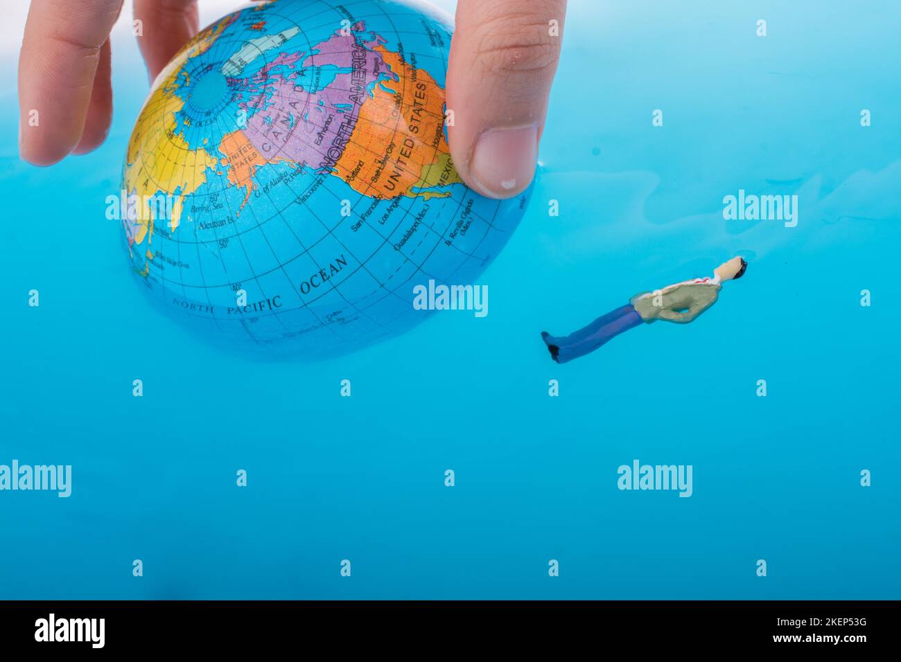 Little globe with floating figurines around in water Stock Photo - Alamy