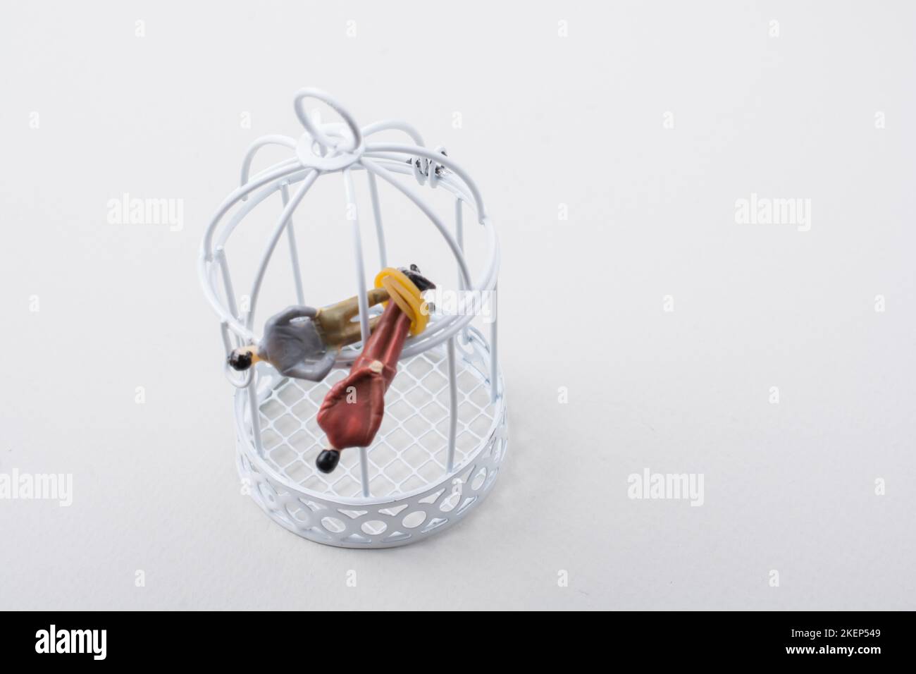 Tiny figurine of men wrapped in rope on a cage Stock Photo - Alamy