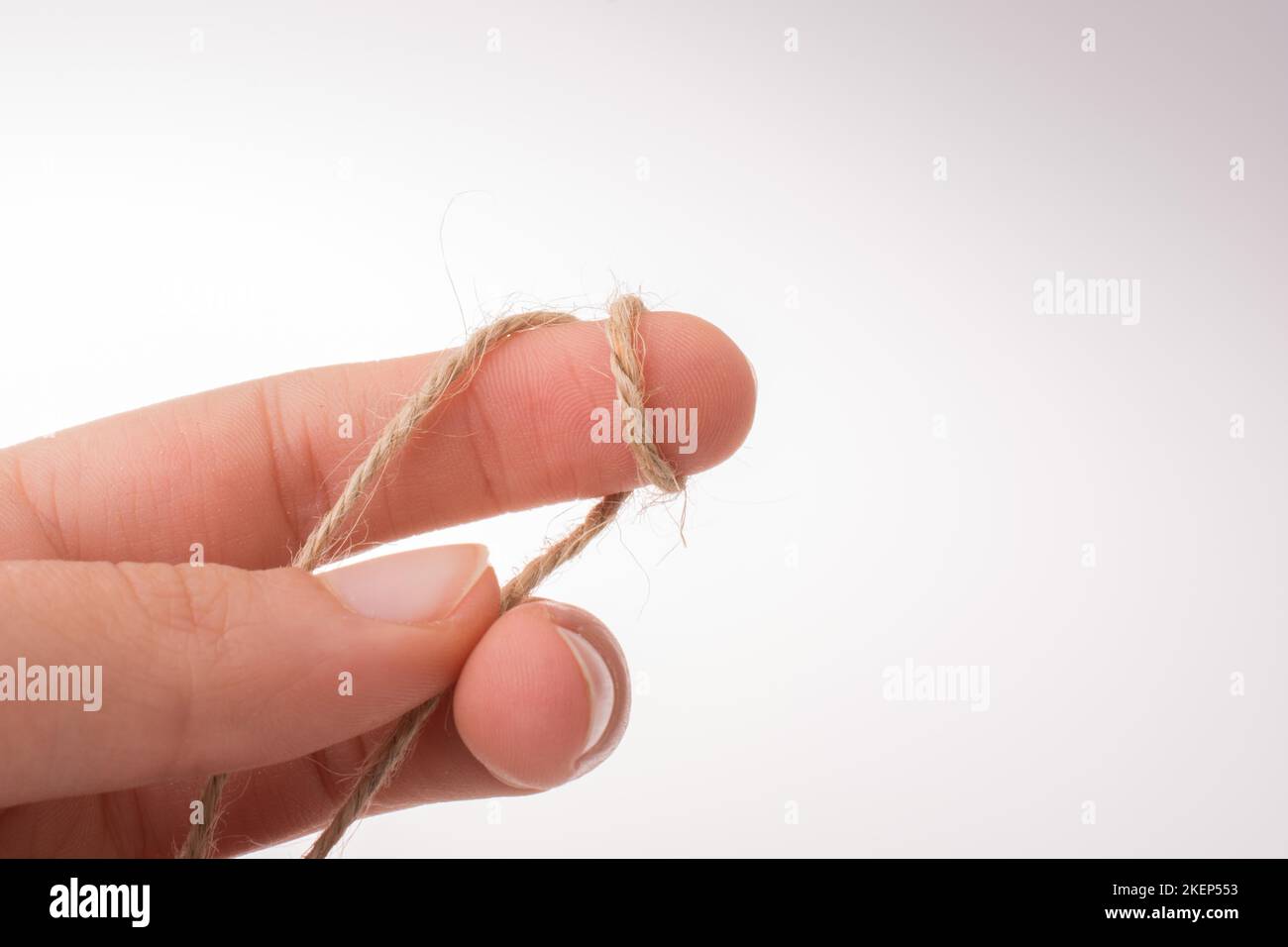 Hand holding linen thread on a white background Stock Photo - Alamy