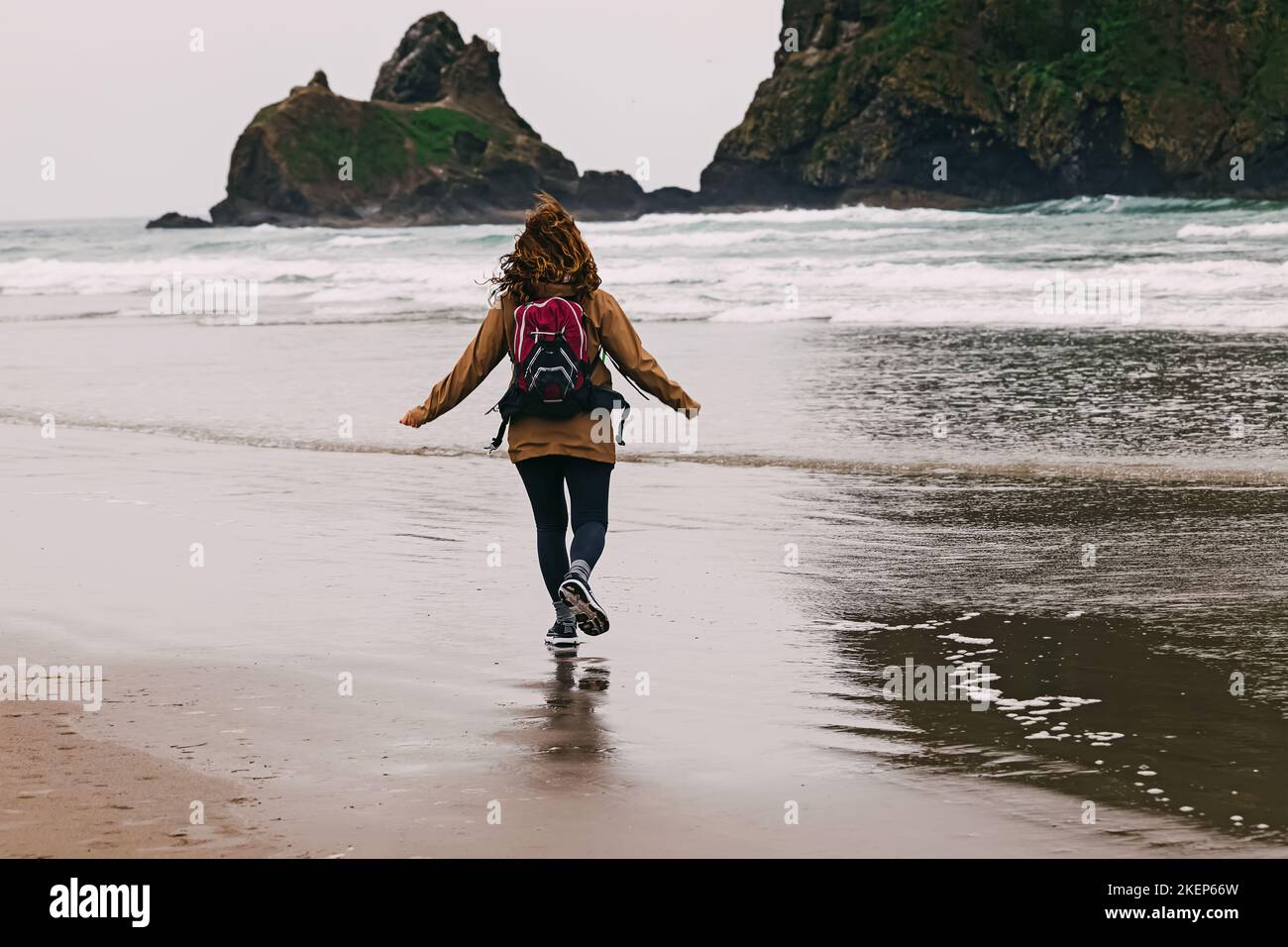 Woman traveler on Oregon Pacific coast at rainy day. Running on the ...