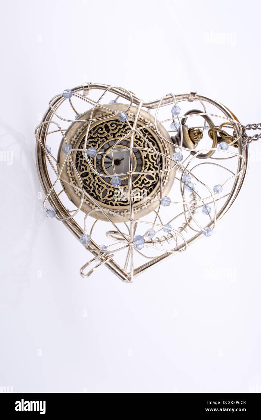 Pocket watch in a heart shaped metal wire cage in hand Stock Photo - Alamy