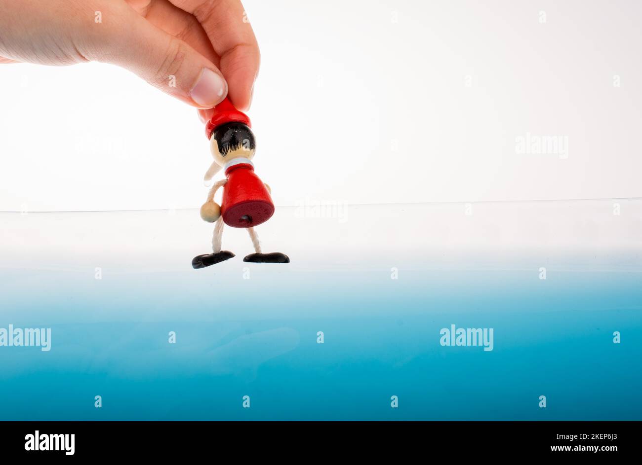 Hand holding wodden puppet Pinocchio on in blue water Stock Photo - Alamy