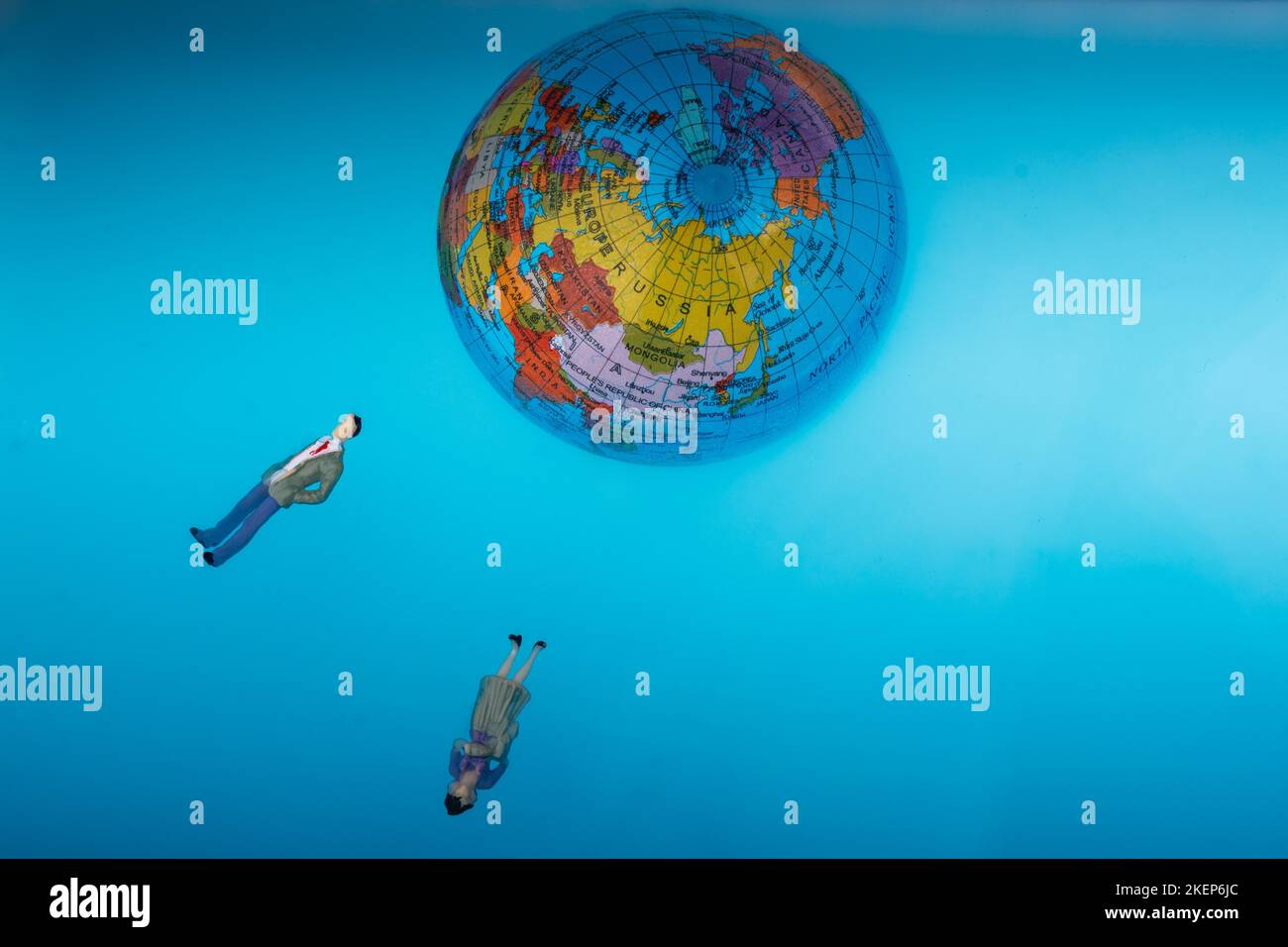 Little globe with floating figurines around in water Stock Photo - Alamy