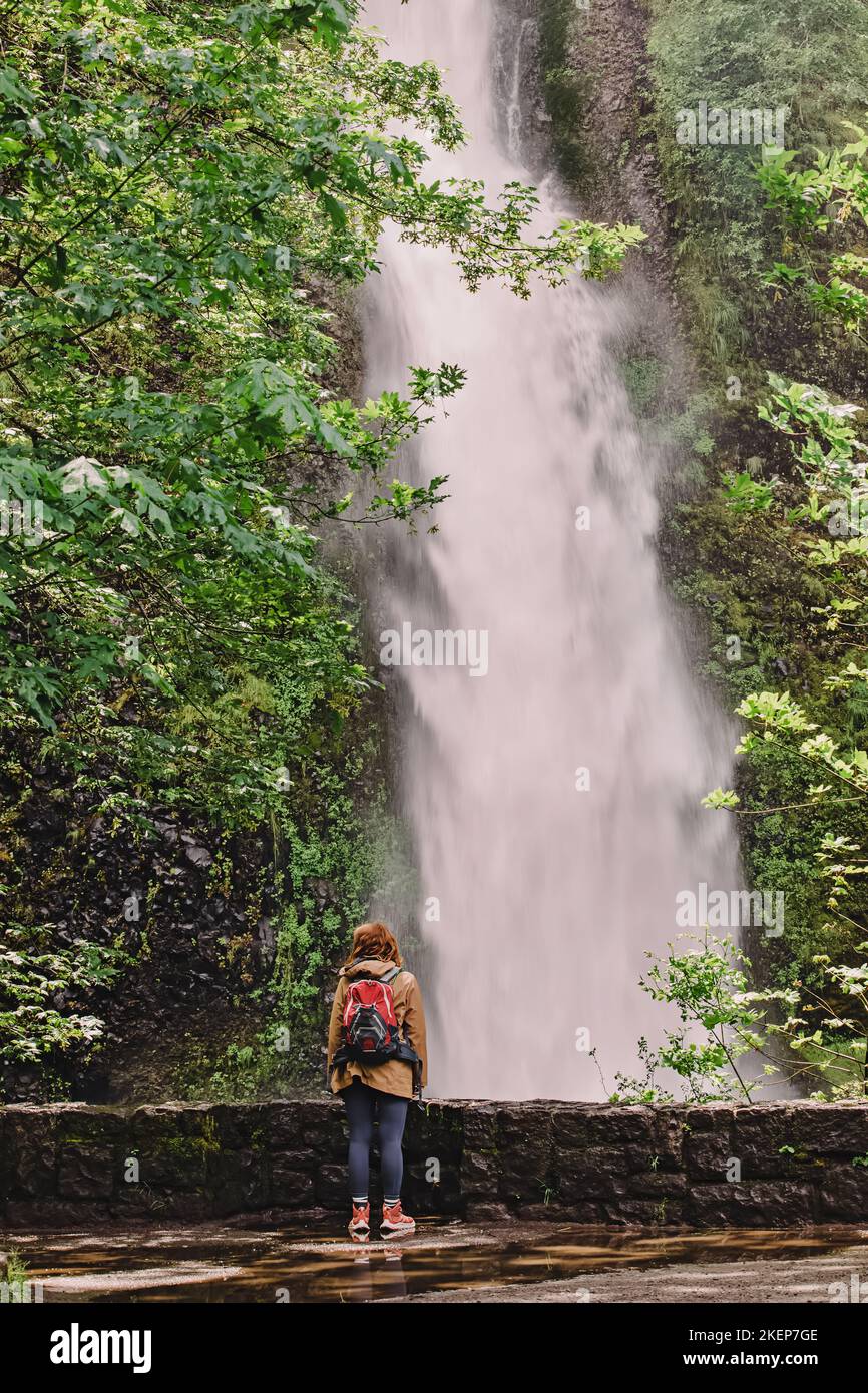 Woman in the raincoat, with a backpack standing near beautiful ...