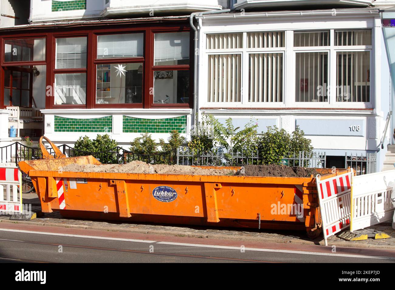 Orange skip for construction waste standing on the road in front of ...