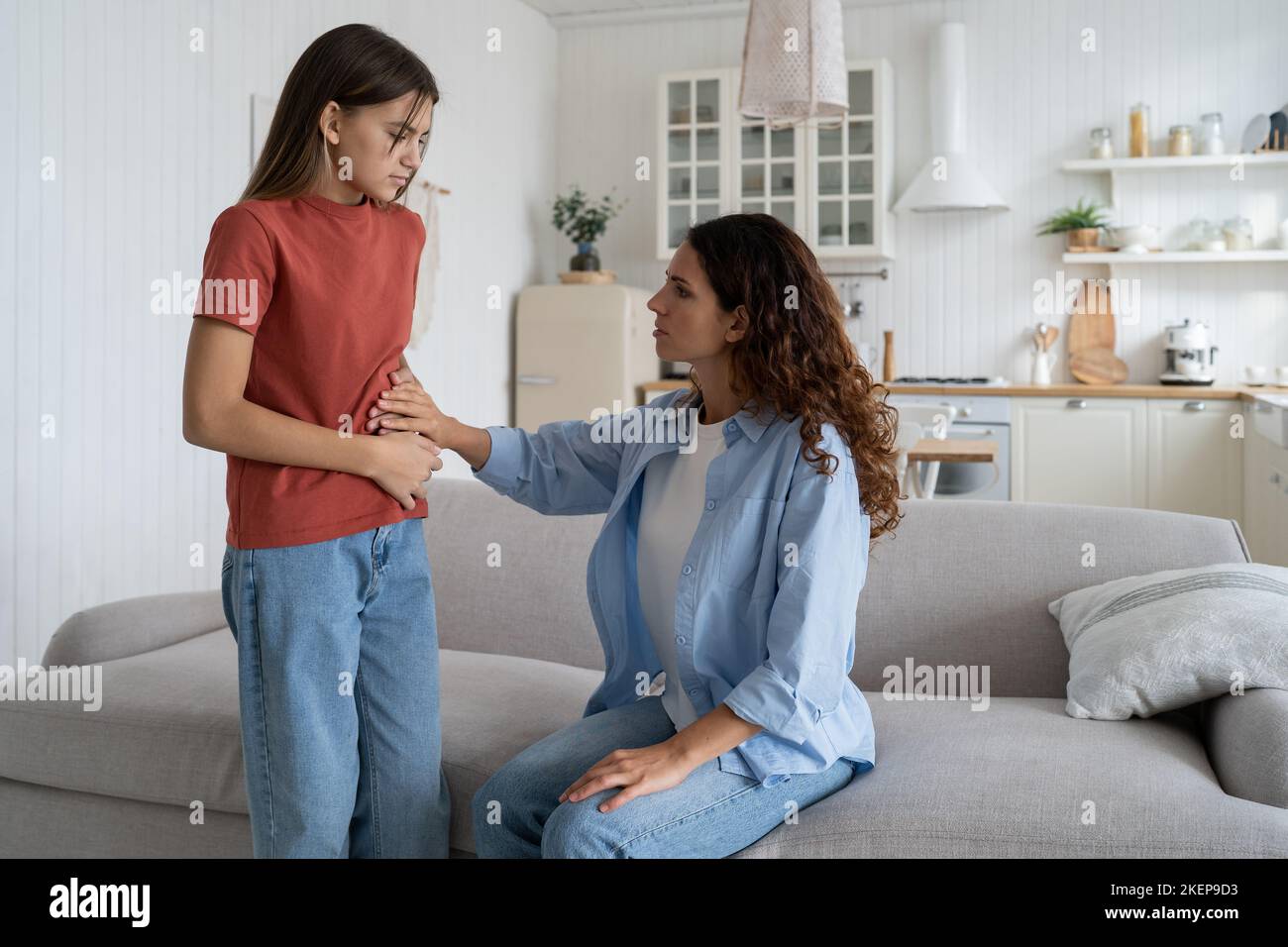 Teenage girl child complaining of stomachache to mother at home ...