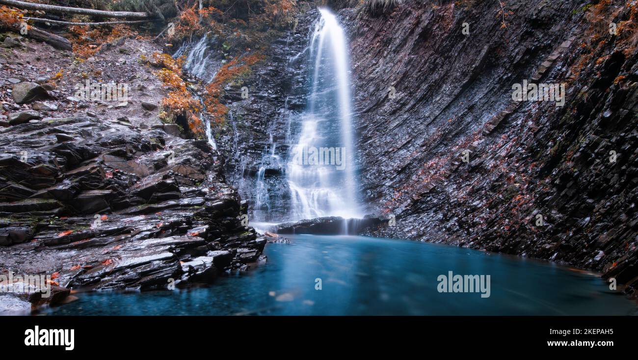 Mountain waterfall. Precipitous stone rock, grass and trees. A ...