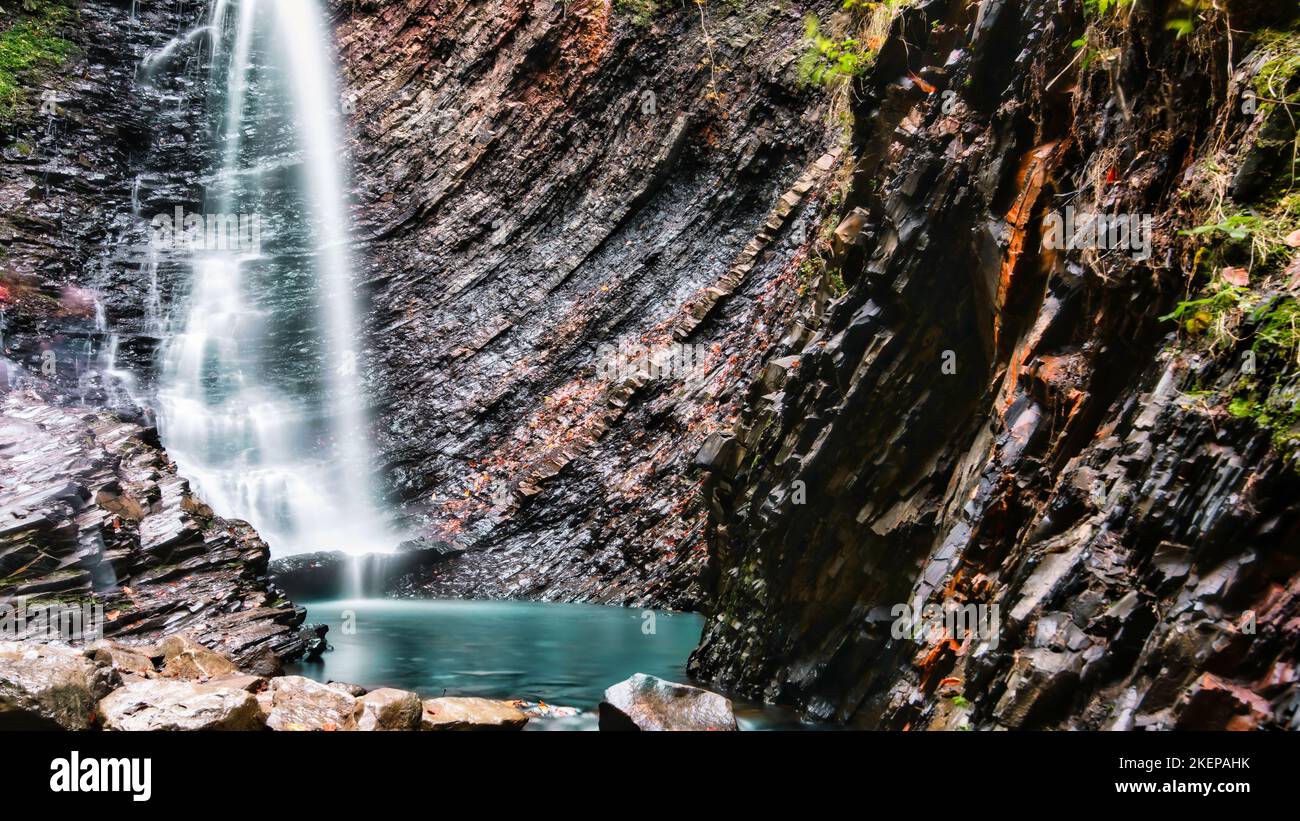 Mountain waterfall. Precipitous stone rock, grass and trees. A ...