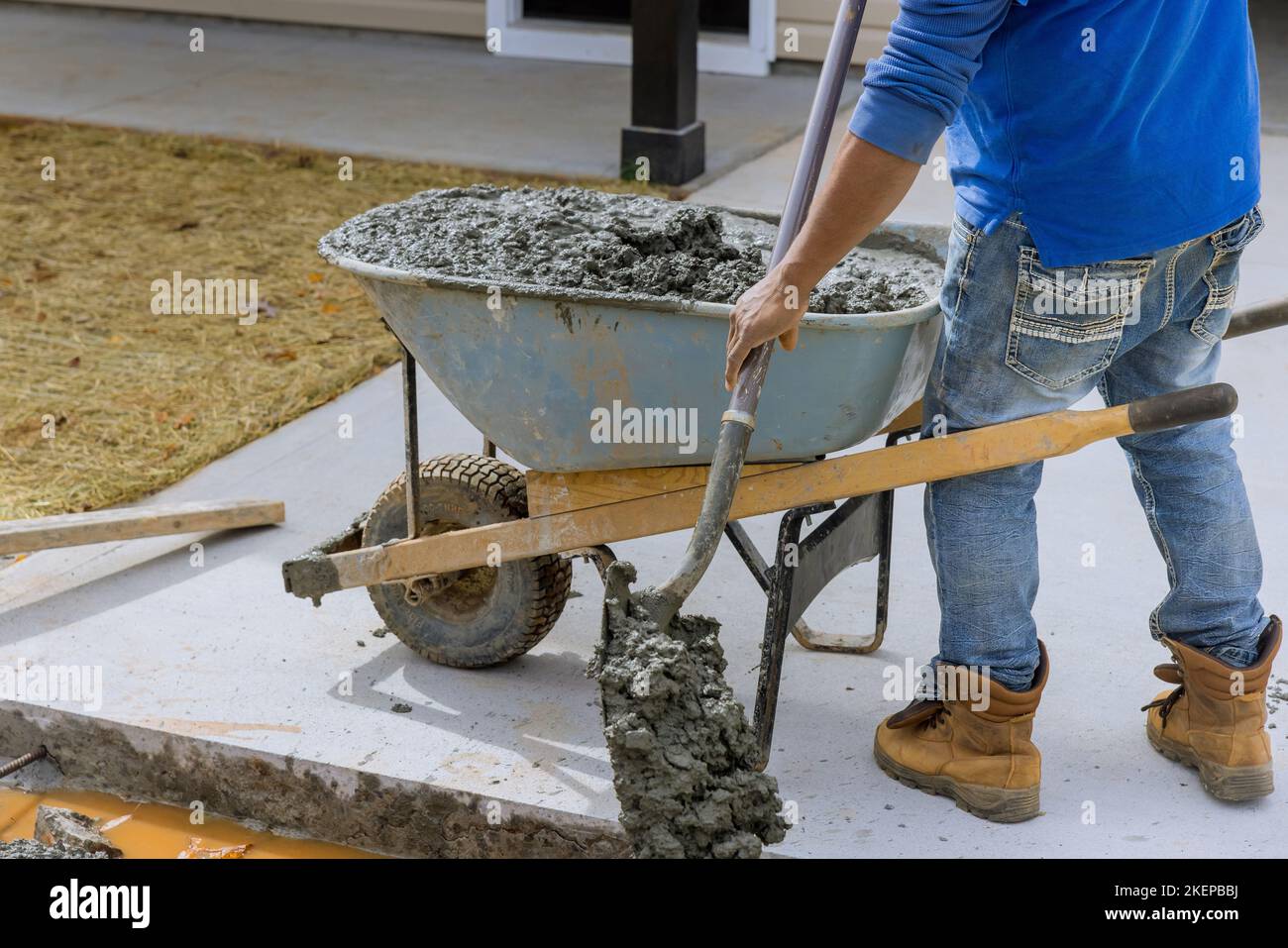 Construction worker pouring cement from wheelbarrow onto to create new ...