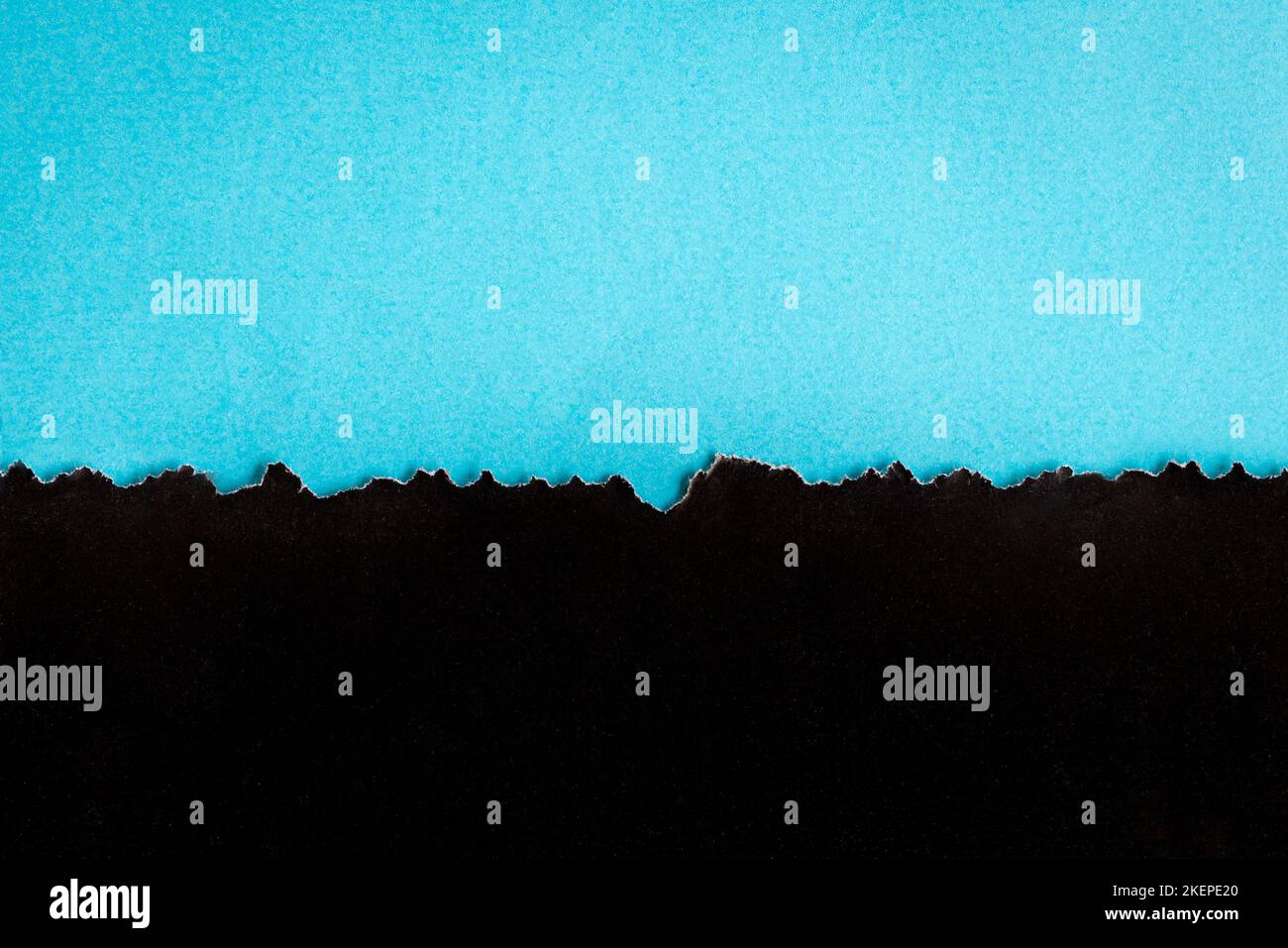 Torn half sheet black paper horizontal on blue paper at the bottom. As ...
