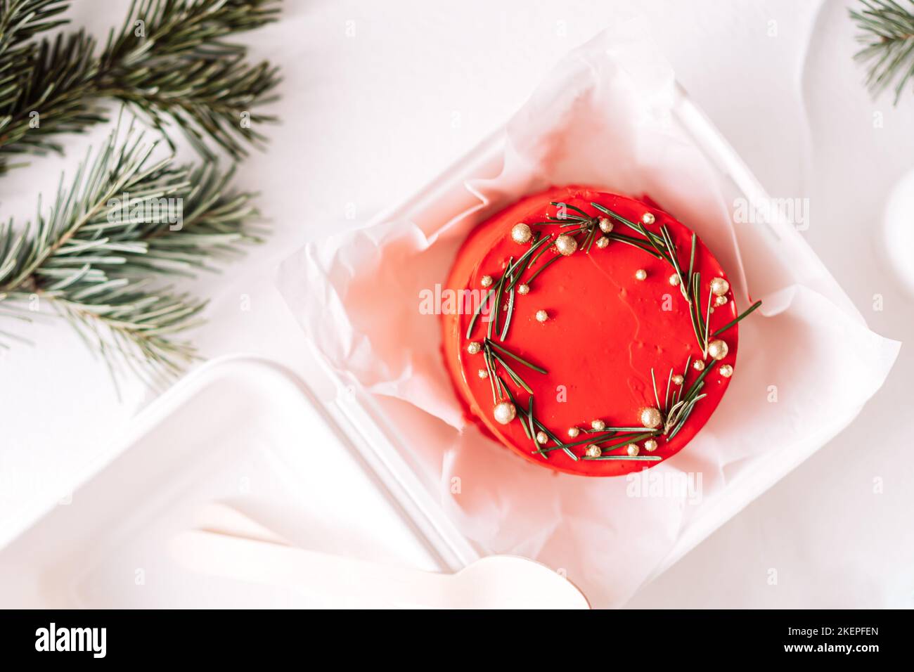 Bento cake red color in a white container next to a Christmas tree ...
