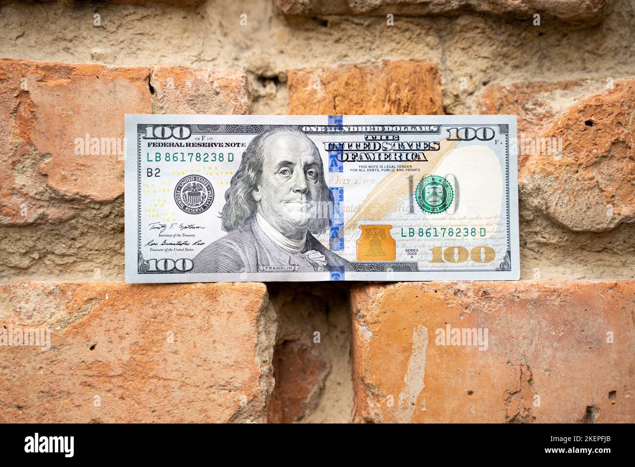 A hundred dollar bill is glued to an old brick wall close-up. Old ...