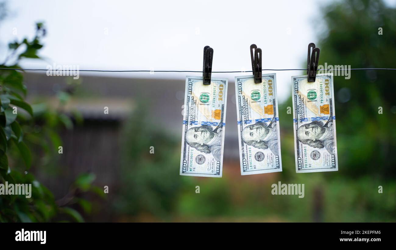 Three hundred dollar bills hanging on a clothes dryer pinned with ...