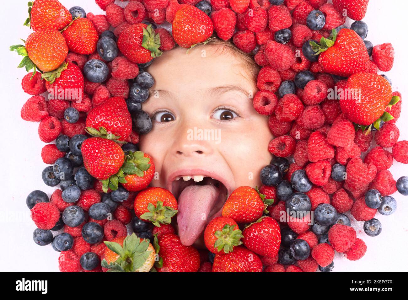 Summer fruits. Berries with kids face close-up. Top view of child face ...