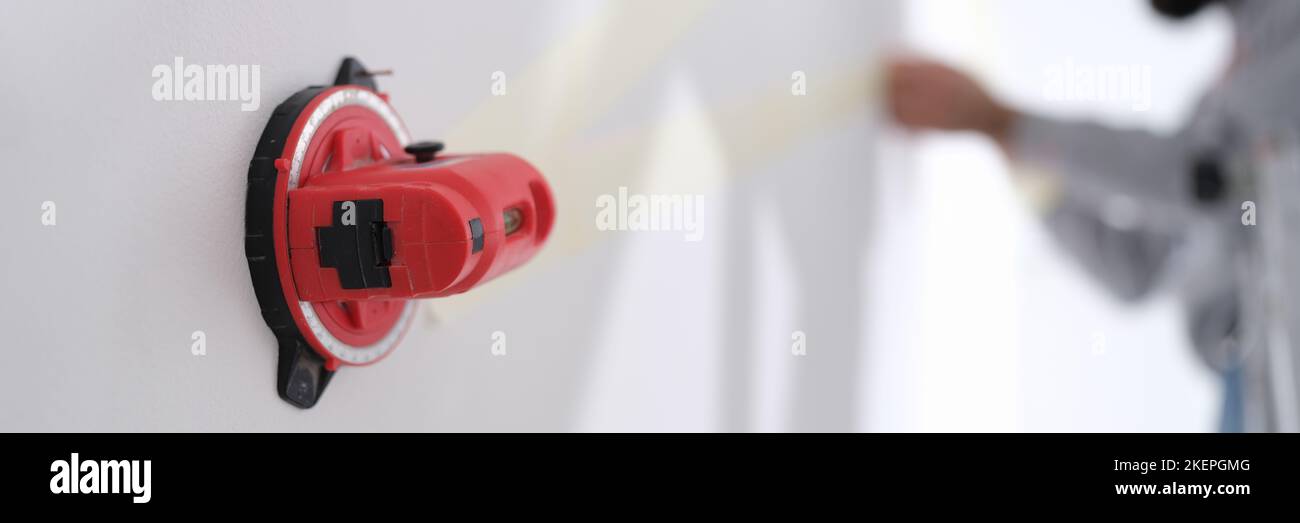 Construction laser level is fixed on wall. Builder makes repairs in ...