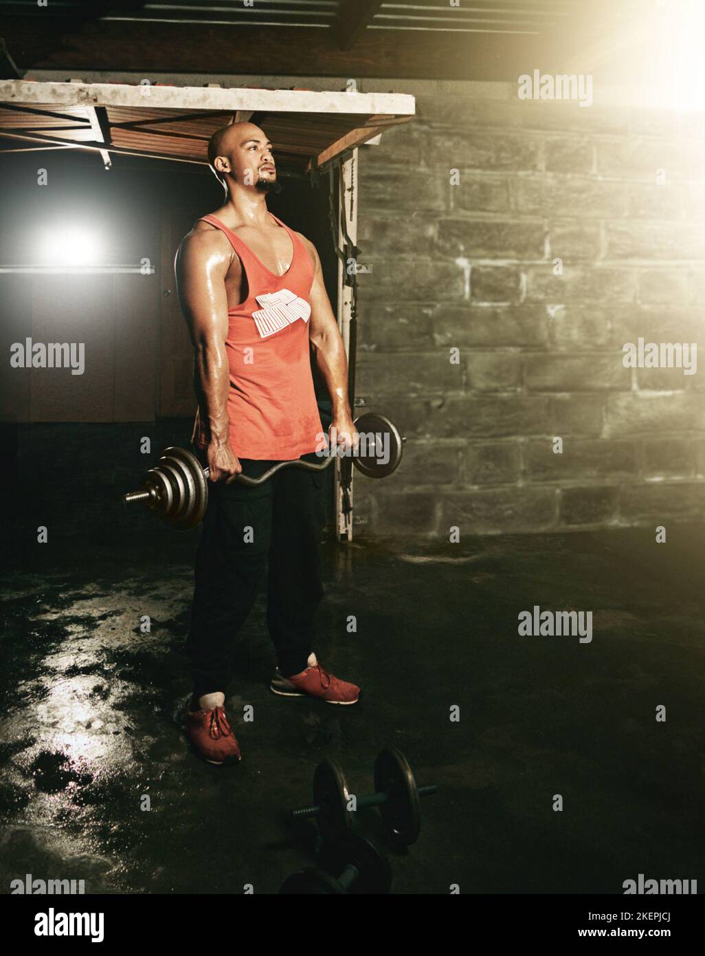 Working with weights. Full length shot of a muscular young man lifting ...