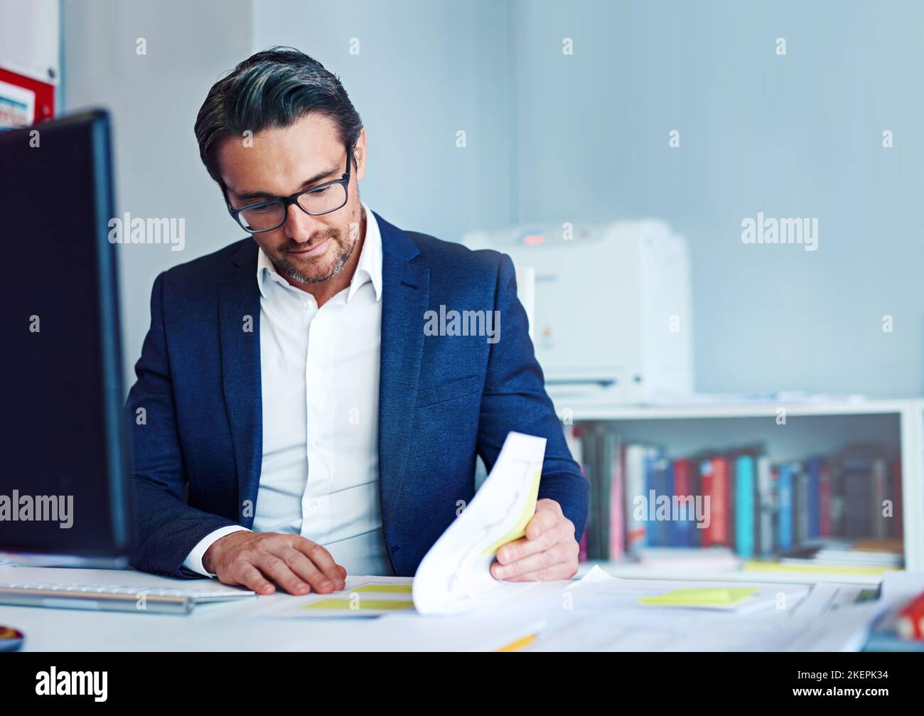Reading through the details. a businessman working at his desk Stock ...