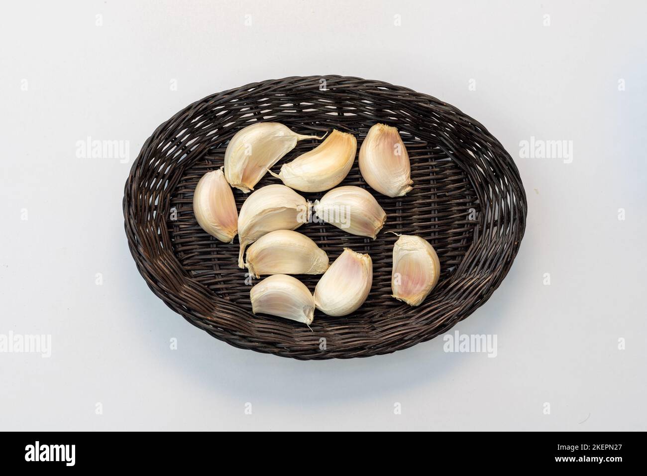 Fresh garlic cloves in a small basket on white isolated background ...
