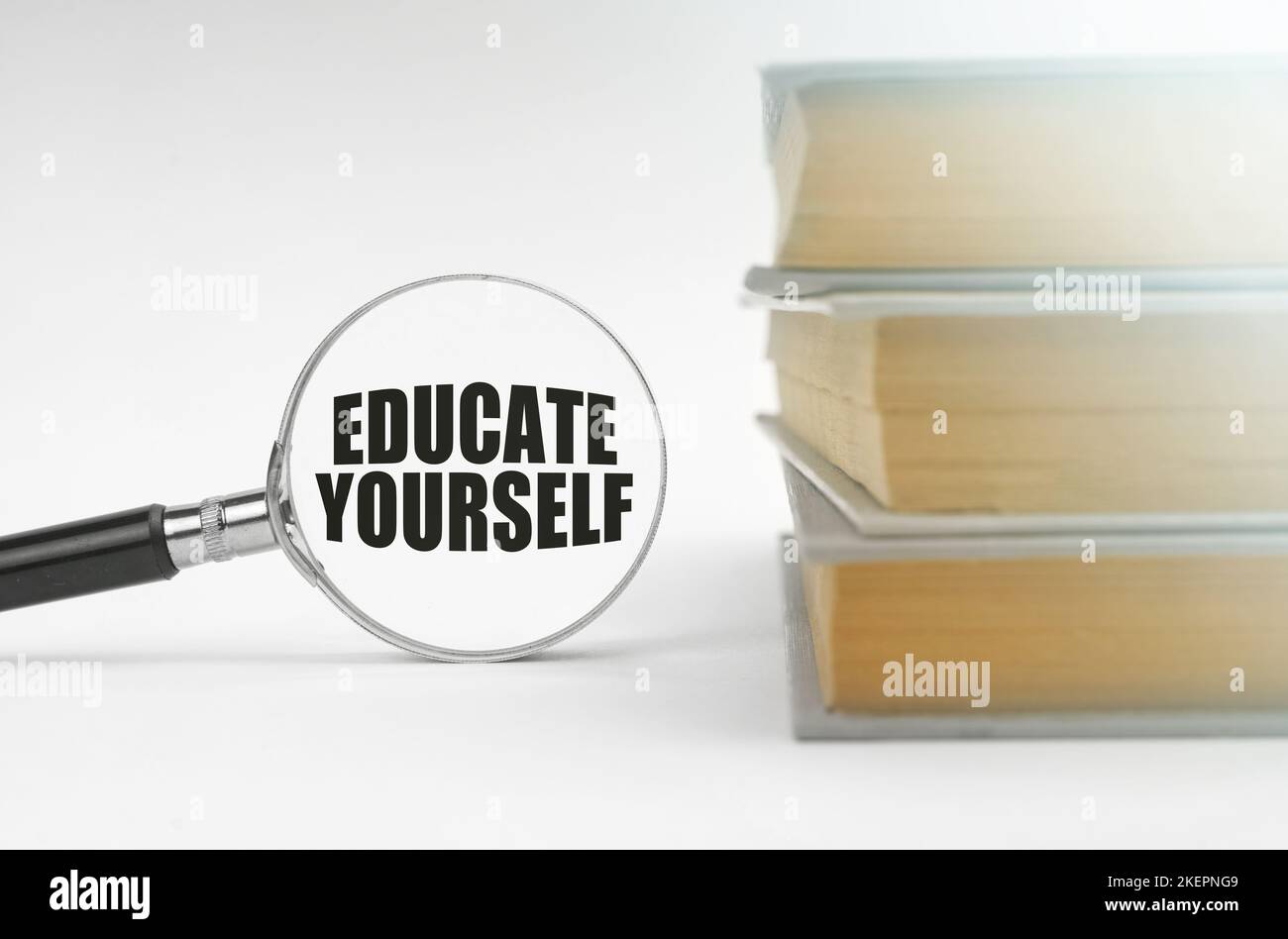 Education concept. On a white background, books and a magnifying glass, inside which it is ...
