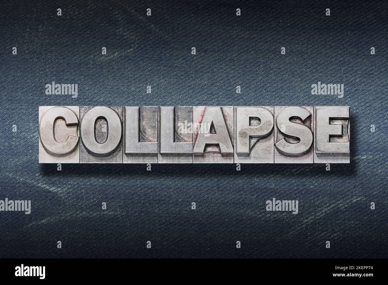 collapse word made from metallic letterpress on dark jeans background ...