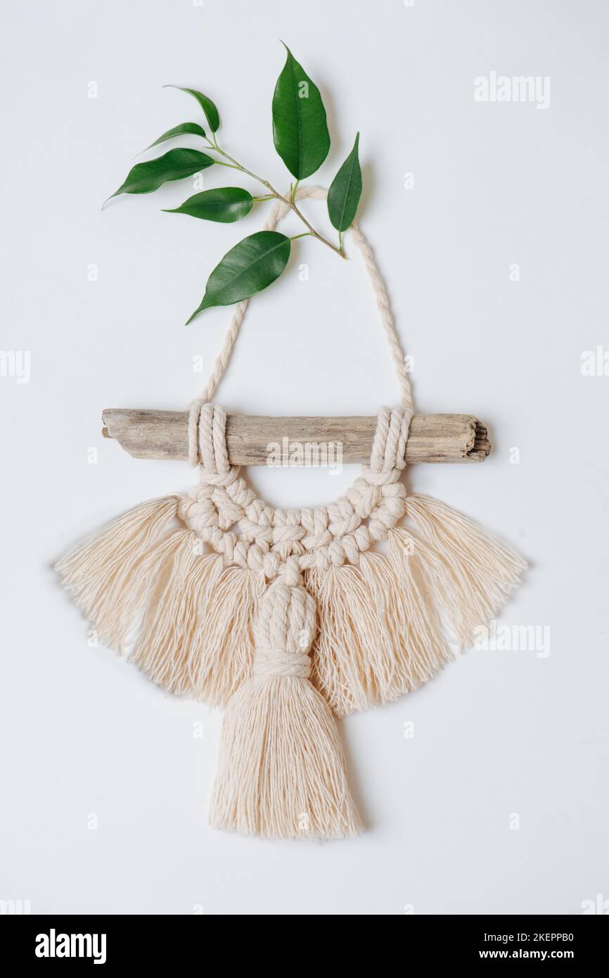 Beautiful macrame on stick hanging on a white wall, decorated with ...