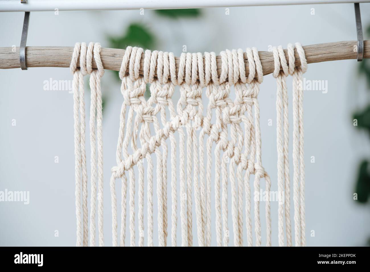 Suspended stick with macrame piece in progress, only partially weaved ...