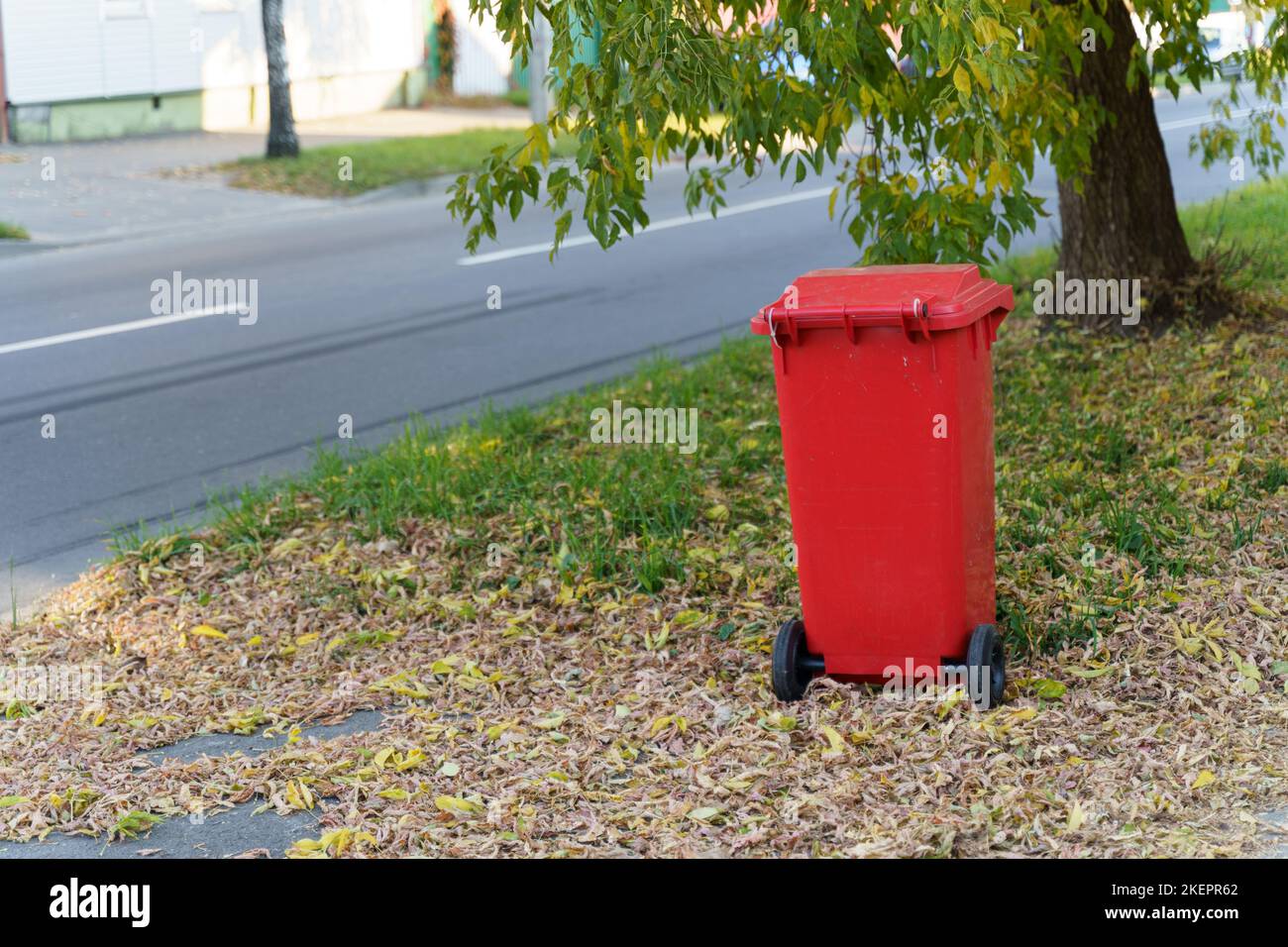 Environmental concept. There is a red plastic waste bin on the street ...