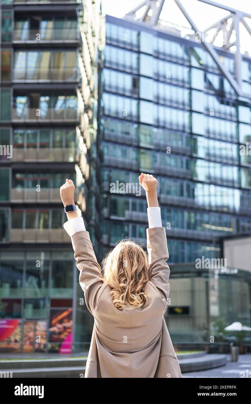 Rear view of corporate woman, lawyer celebrating, lifting hands up and ...