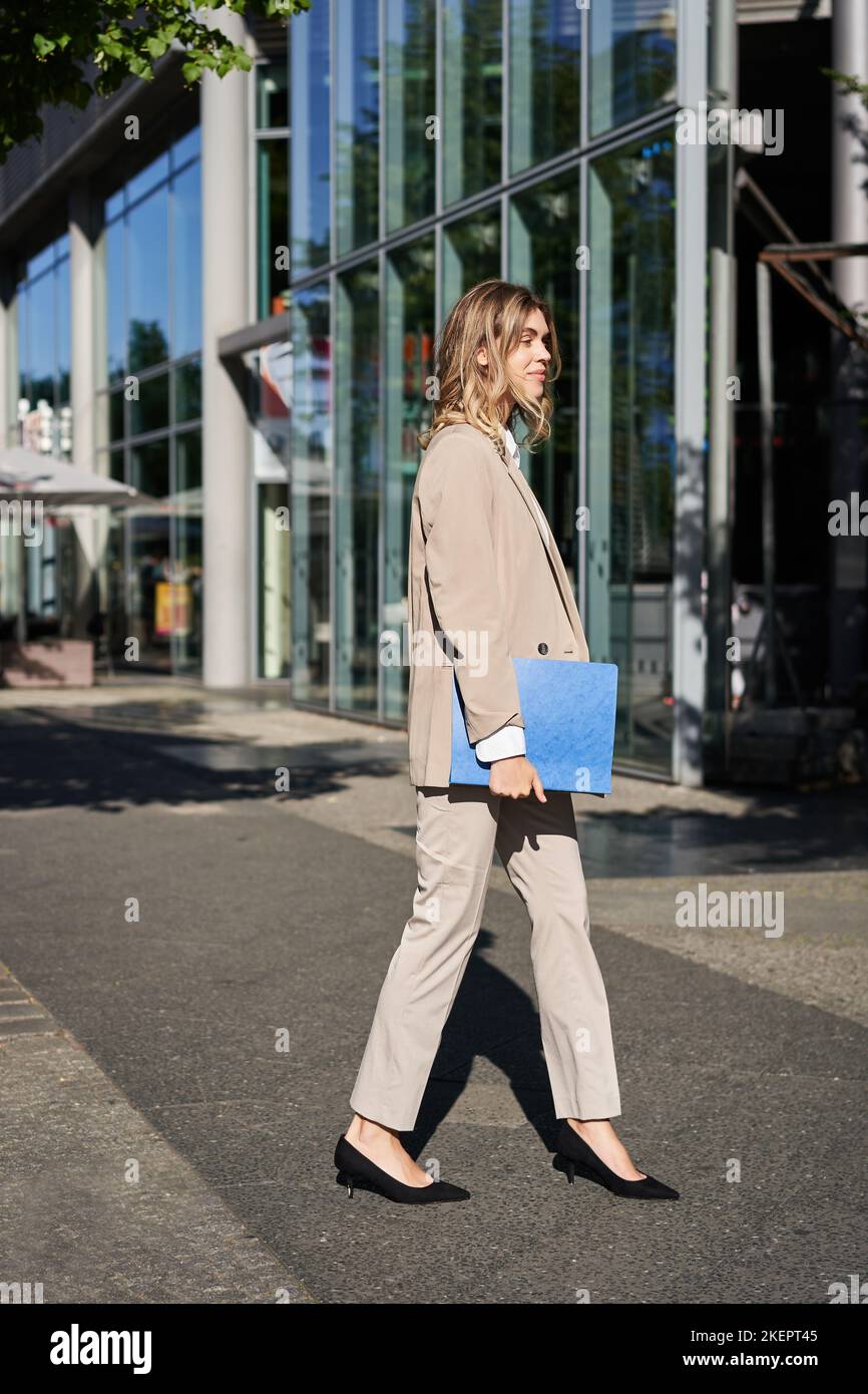Portrait of businesswoman in beige suit and high heels walking on ...