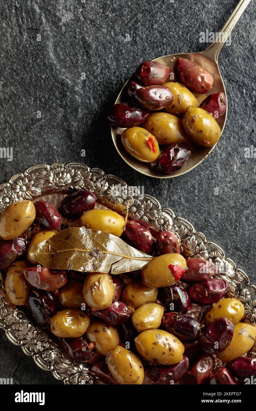 Spicy olives on a black stone table. Top view Stock Photo - Alamy