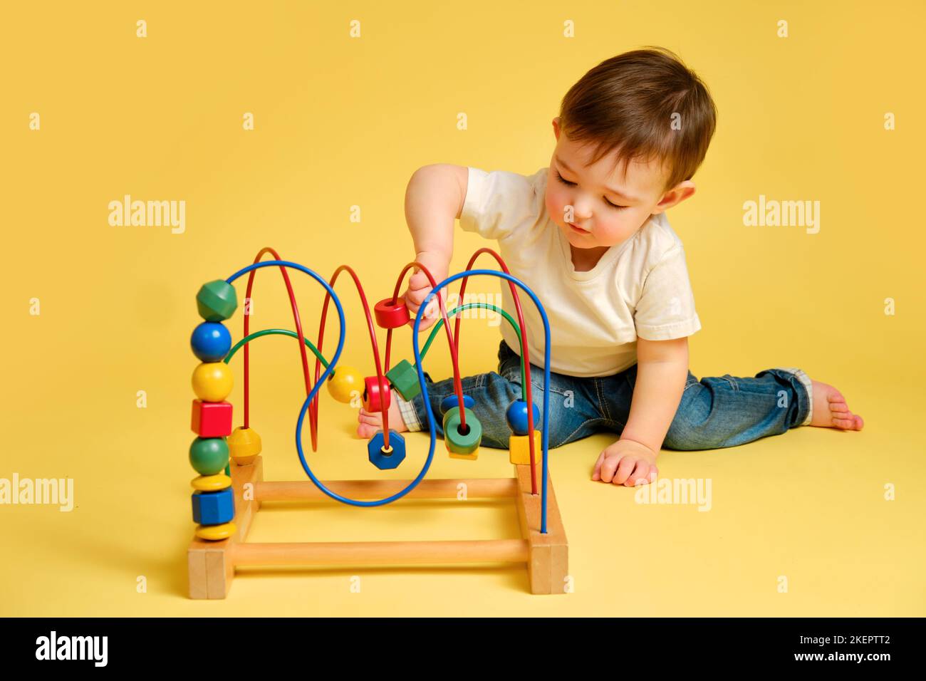 Toddler baby is playing logic educational games on a studio yellow ...