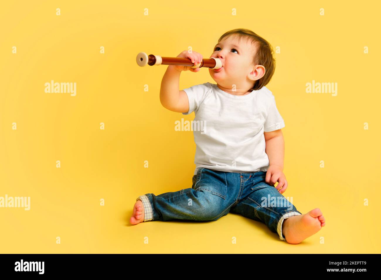 Toddler baby plays the flute, a child with a wind musical instrument on ...