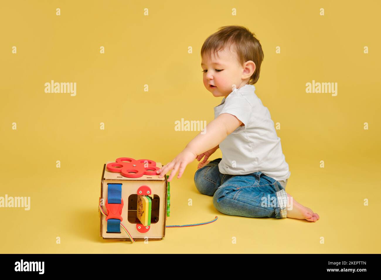 Toddler baby is playing logic educational games busyboard on a studio ...