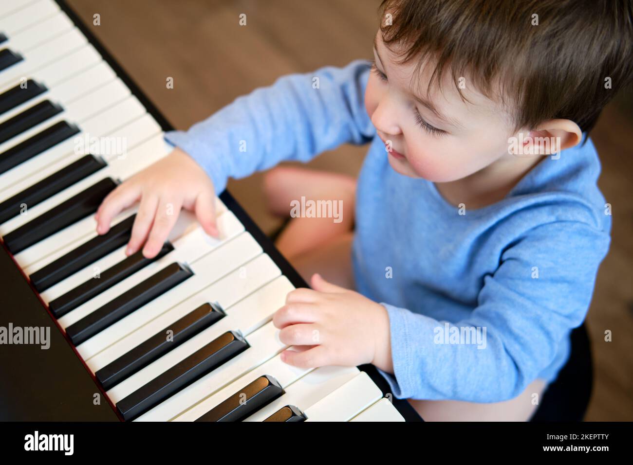 Toddler baby plays piano in home living room, music lessons. Happy ...