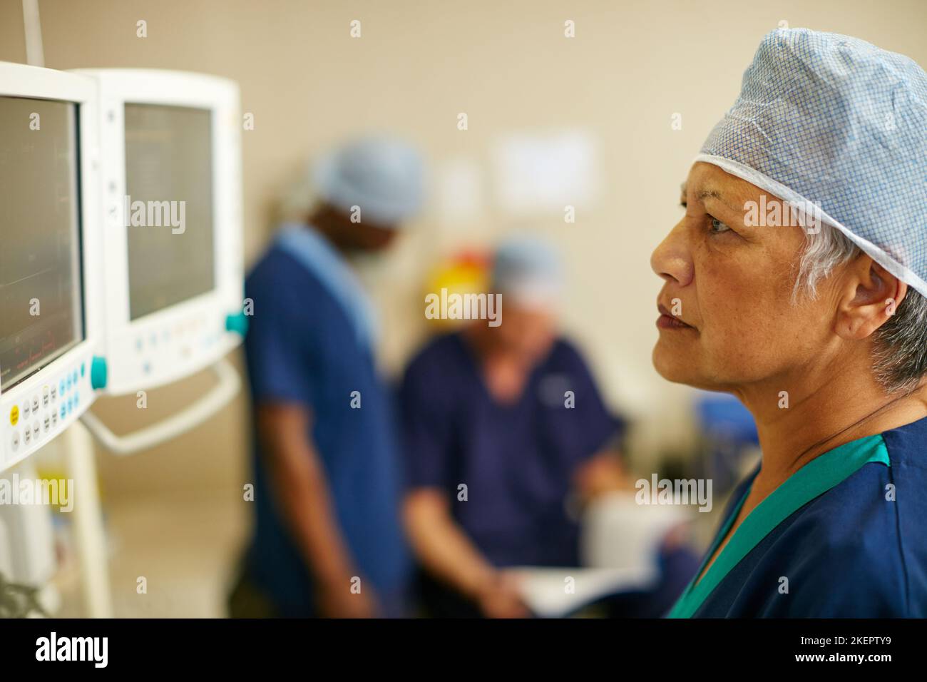Keeping a close eye on her patients vitals. a surgeon looking at a ...