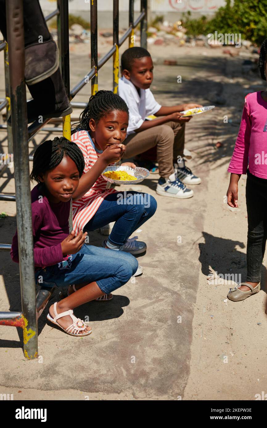 Eating on the playground. Full length portrait of children getting fed ...