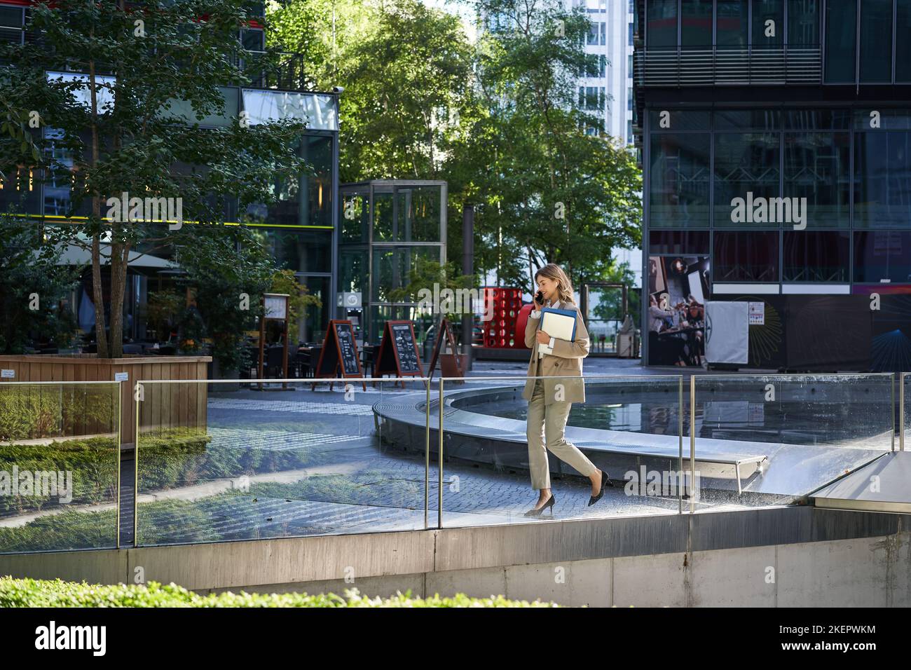 Businesswoman in suit, walking in city, going to work with laptop and ...