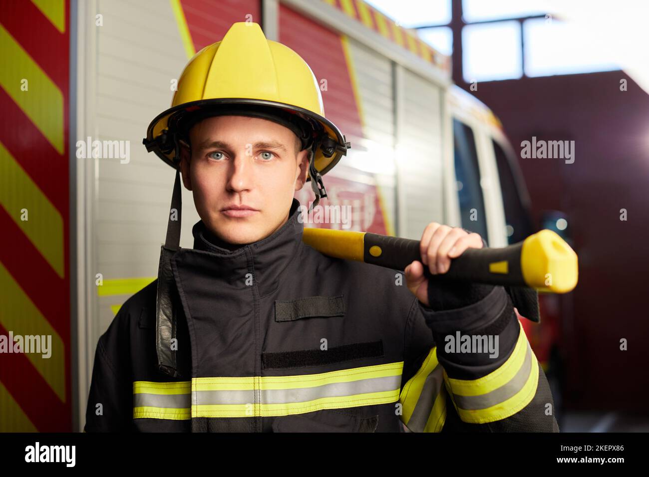 Firefighter fully equipped with helmet and ax in fire truck background ...