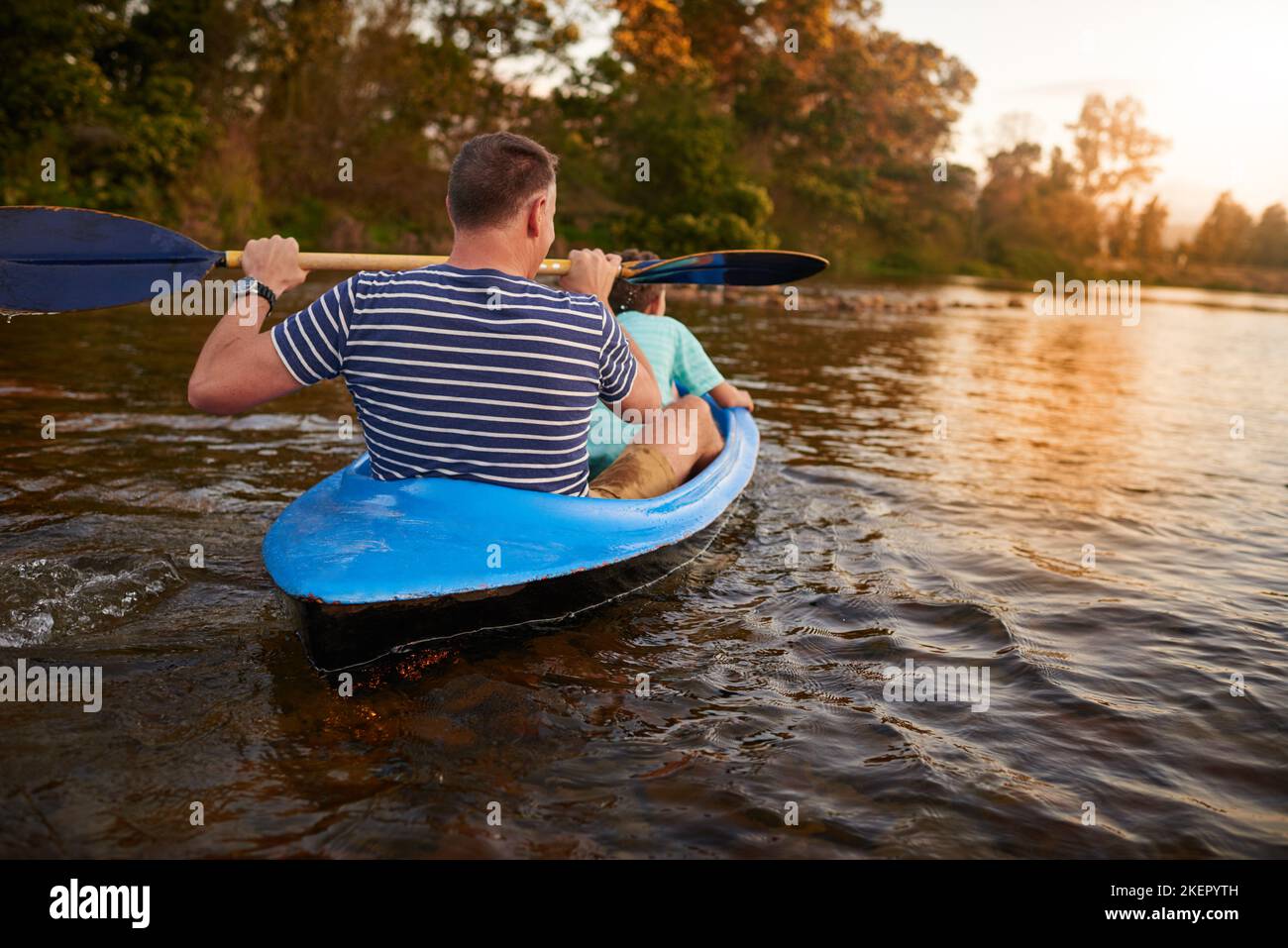 Paddling down the river. a father and son rowing a boat together on a ...